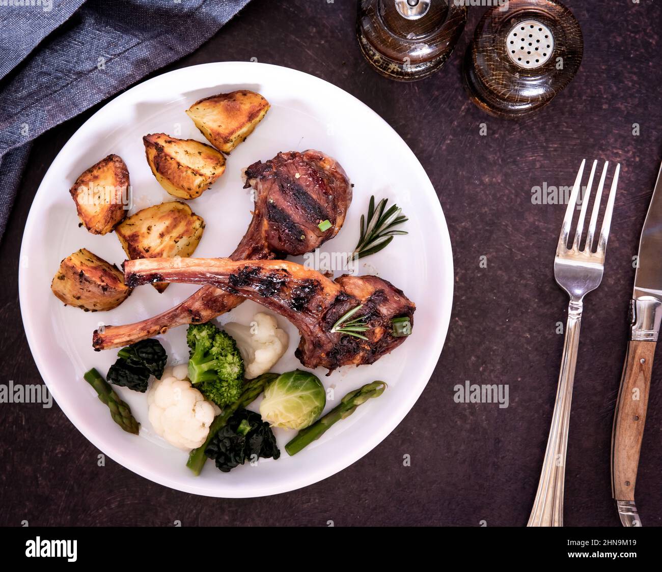 Top down view of a plated grilled lamb chops meal with potatoes and ...