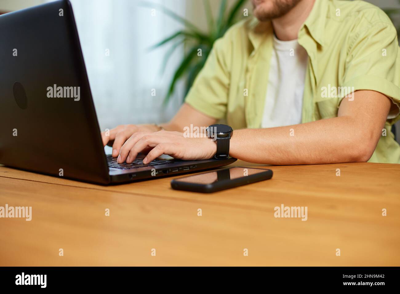 Man hands typing something on laptop, working on computer at home or ...