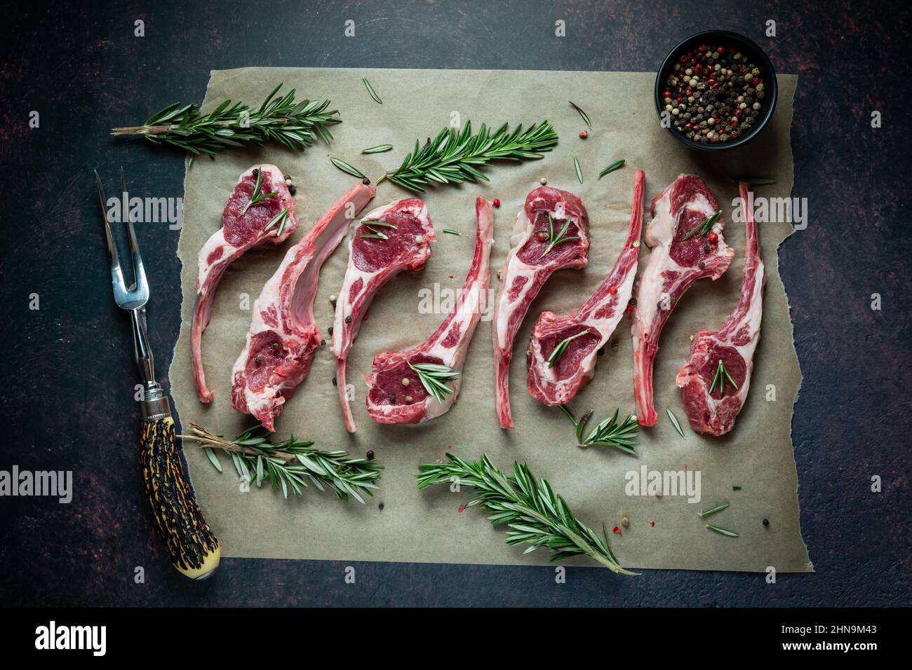 Raw lamb chops on parchment paper with rosemary and peppercorns Stock ...