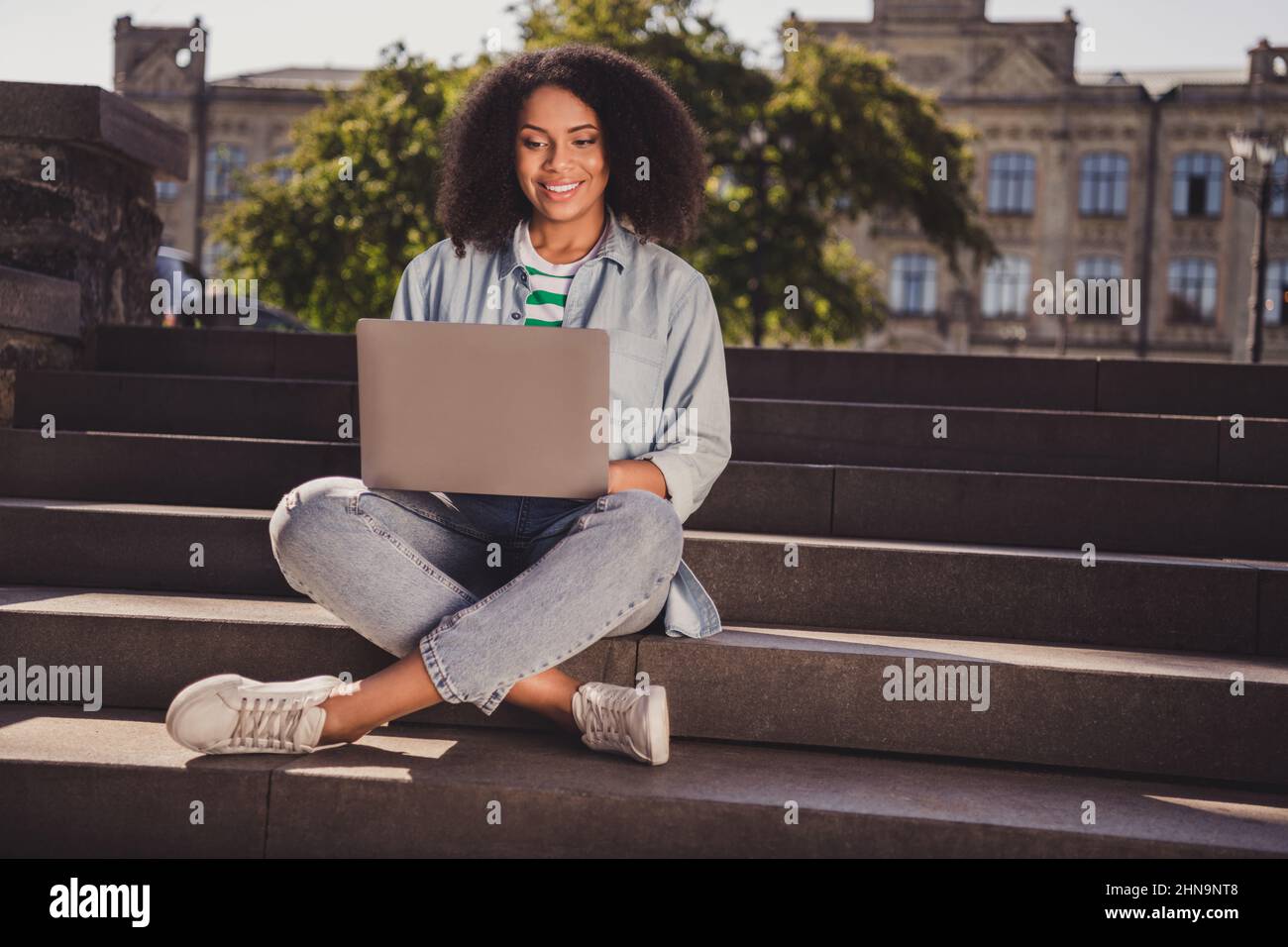 Portrait of attractive cheerful girl sitting on stairs spending free ...