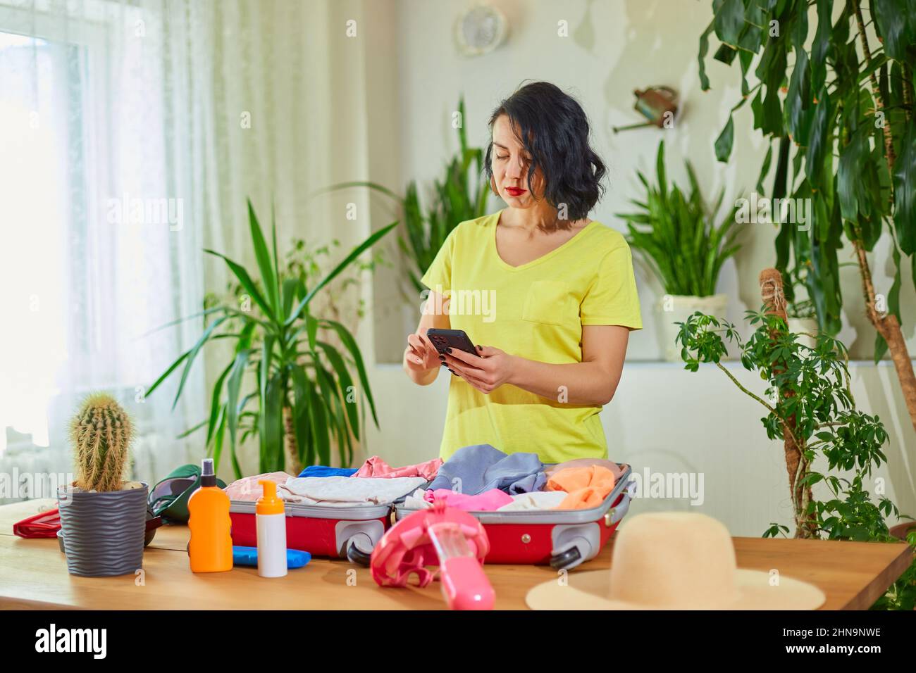 Travel woman packing suitcase, check things on the smartphone, getting ...