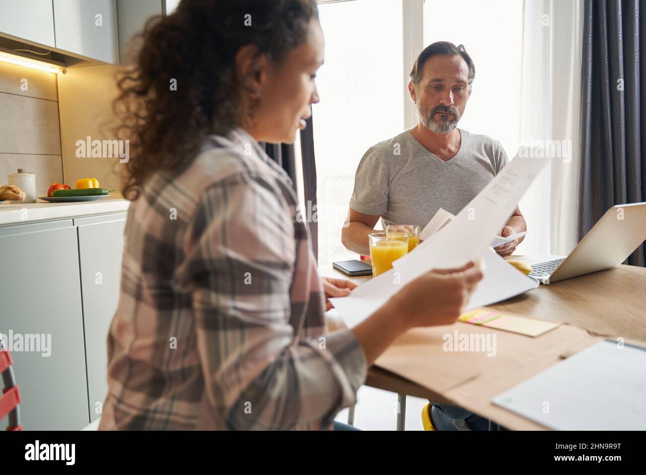 Couple examining documents at the table in kitchen Stock Photo - Alamy