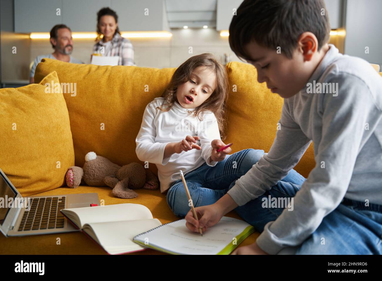 Boy writing homework exercise in notebook with sister Stock Photo - Alamy
