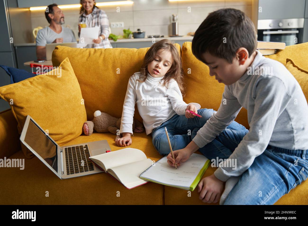 Hard-working kid preparing homework for school on couch Stock Photo - Alamy