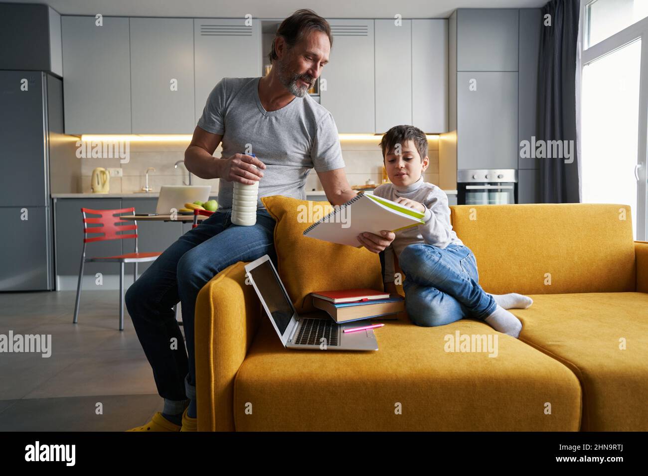 Parent sitting on sofa side and helping boy with homework Stock Photo ...