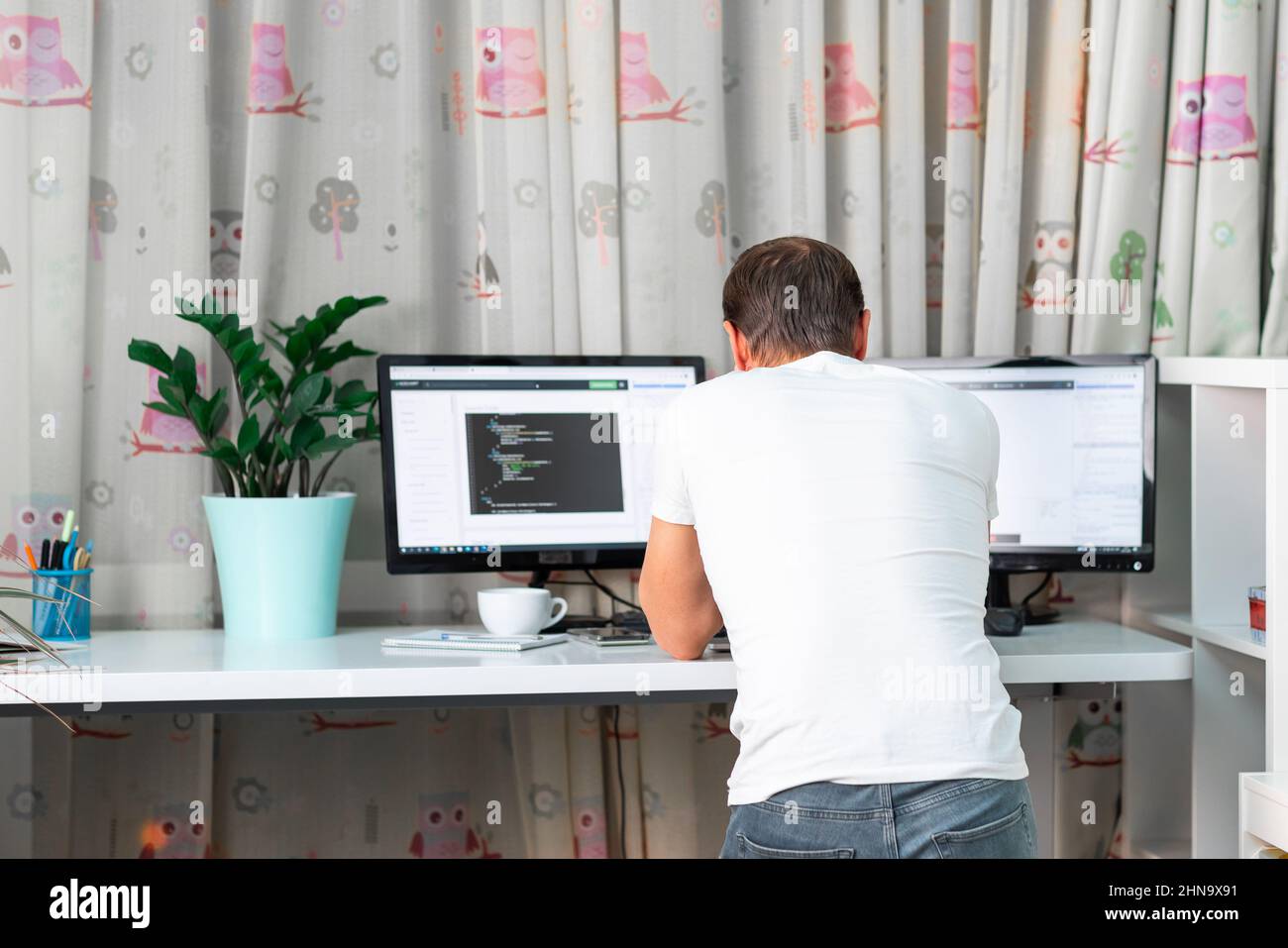 Man working on computer at standing desk at home office. Freelancer ...