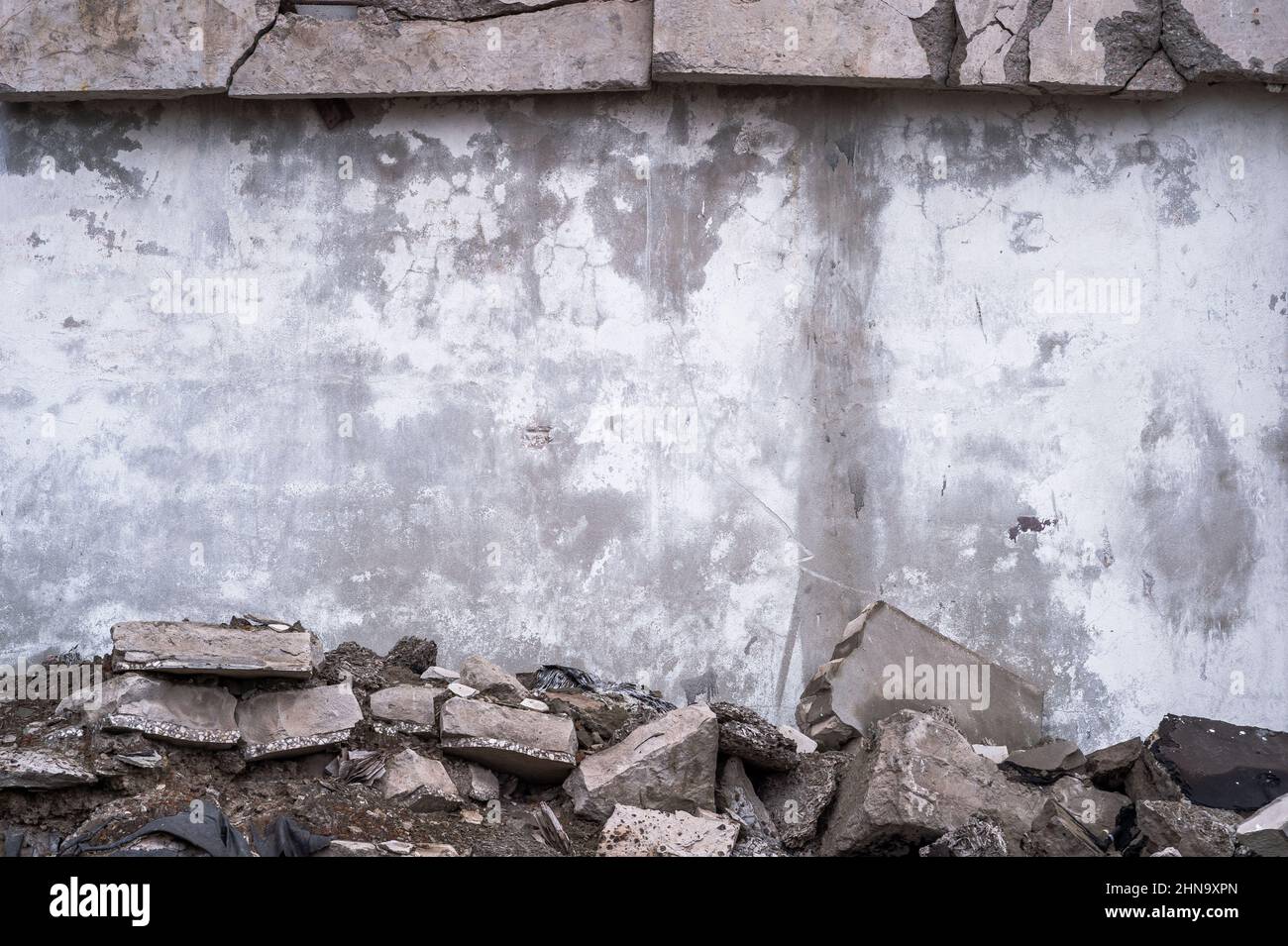Concrete wall with remnants of white plaster framed by construction ...