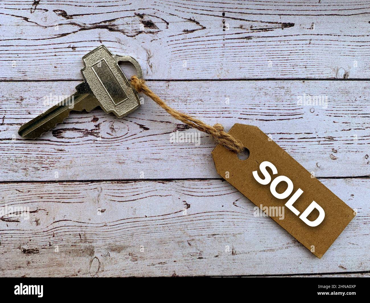 Text on brown tag with house key and wooden table background - Sold ...