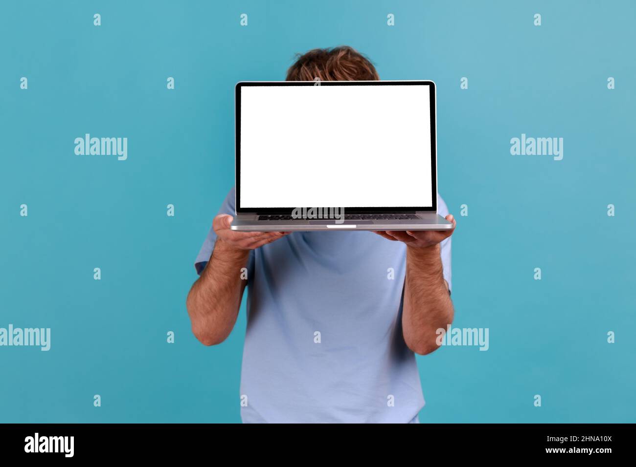 Portrait of unknown man hiding face behind laptop with white empty ...