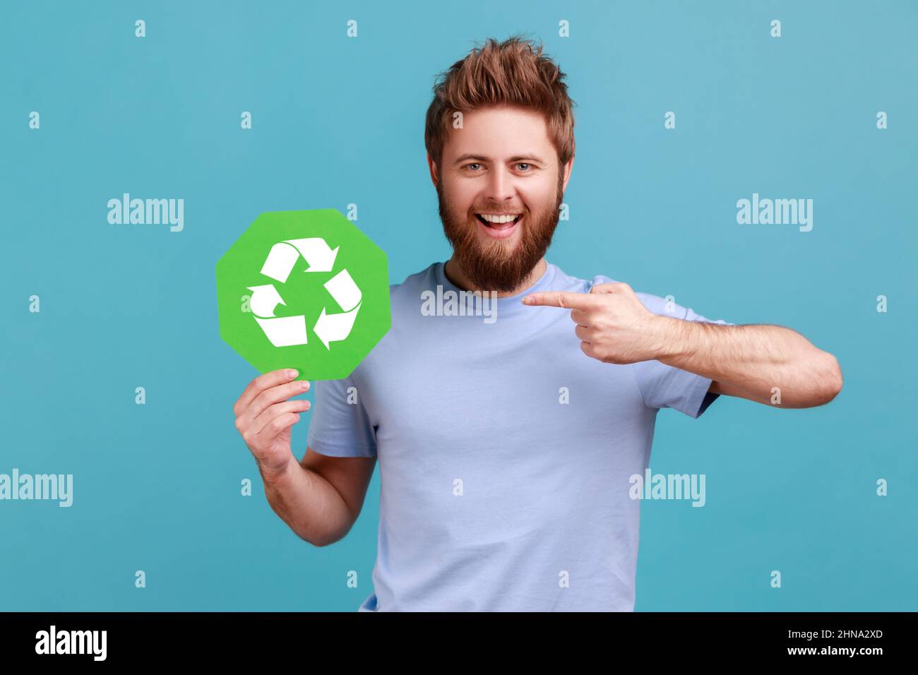 Portrait of optimistic bearded man pointing finger at waste recycling ...