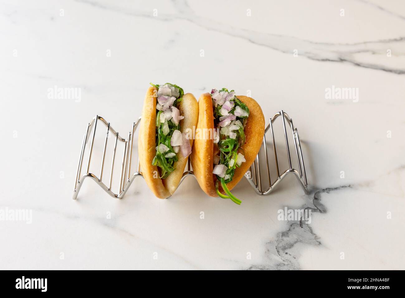 White tacos with different foods placed on a special stand lined up on ...