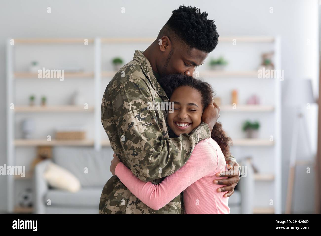 Side view of man in military uniform hugging child Stock Photo - Alamy