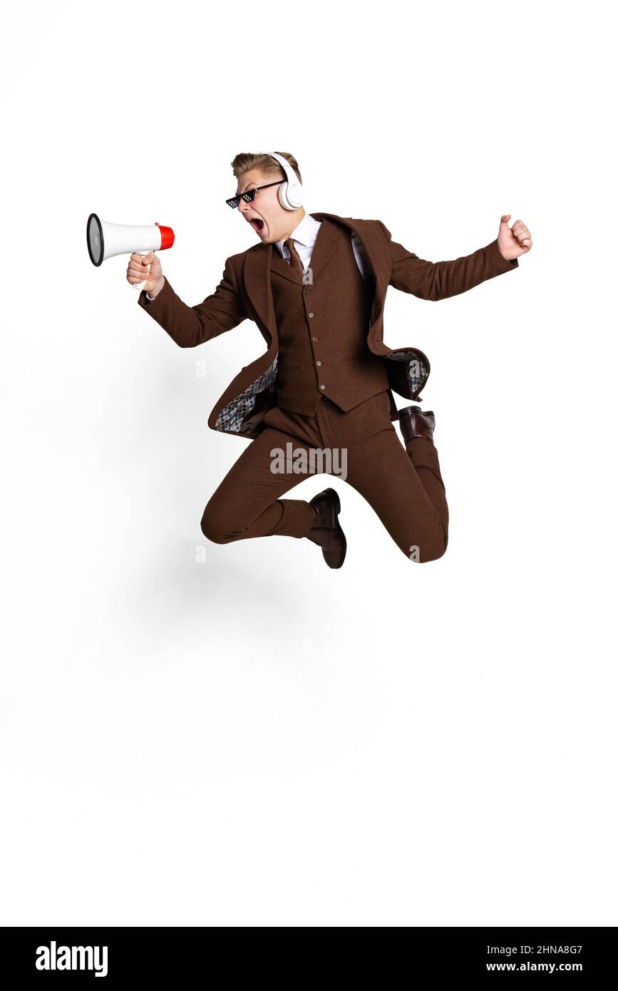 Excited young businessman, student, diplomat jumping with megaphone ...