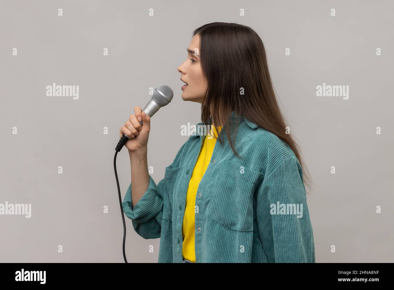 Side view portrait of young adult woman journalist holding microphone ...