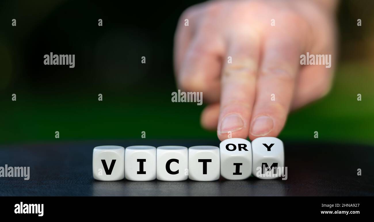 Hand turns dice and changes the word victim to victory Stock Photo - Alamy