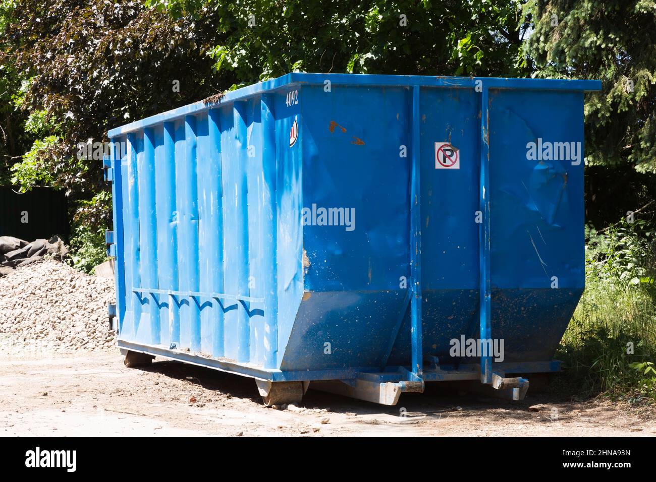 Large blue painted metal bin for dumping discarded materials and debris ...
