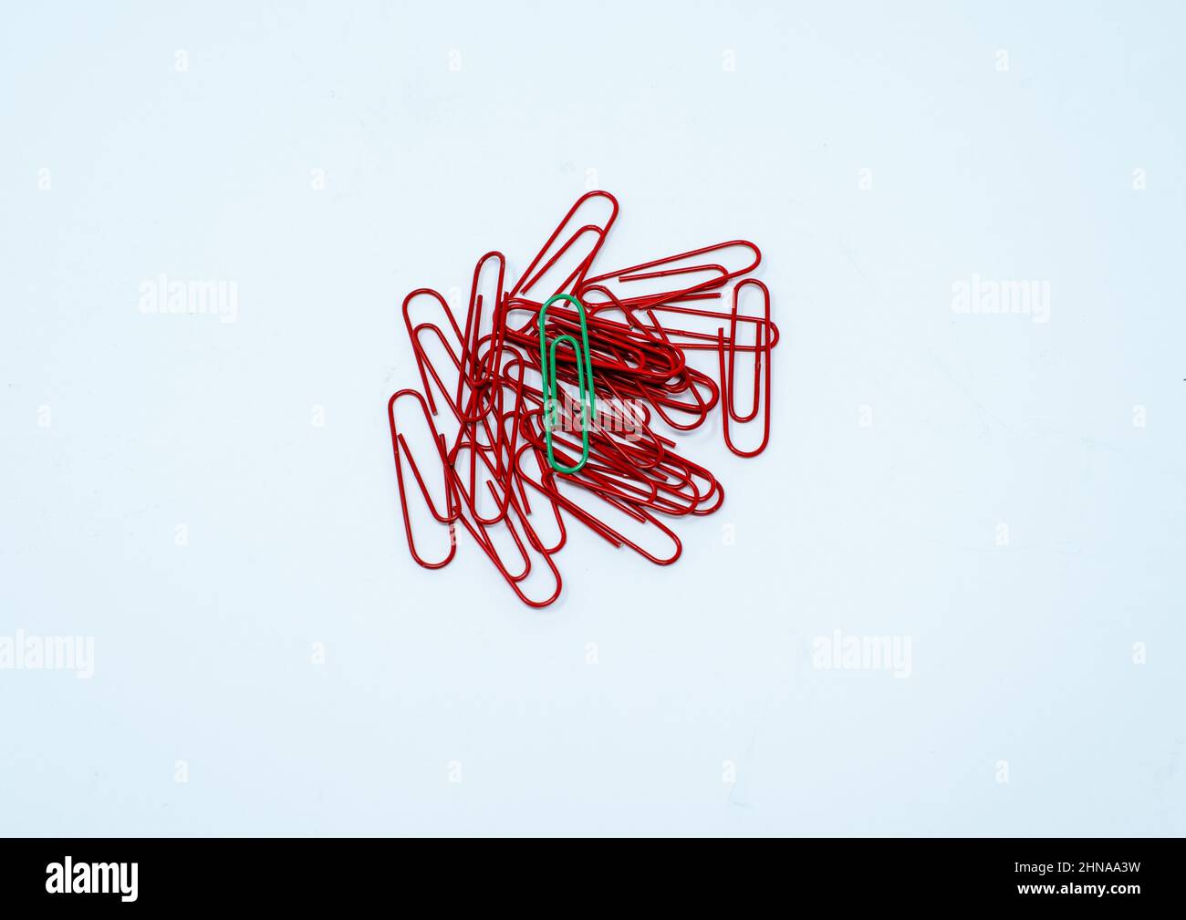 Multi coloured, red and green paper clips in a pile on a plain white ...