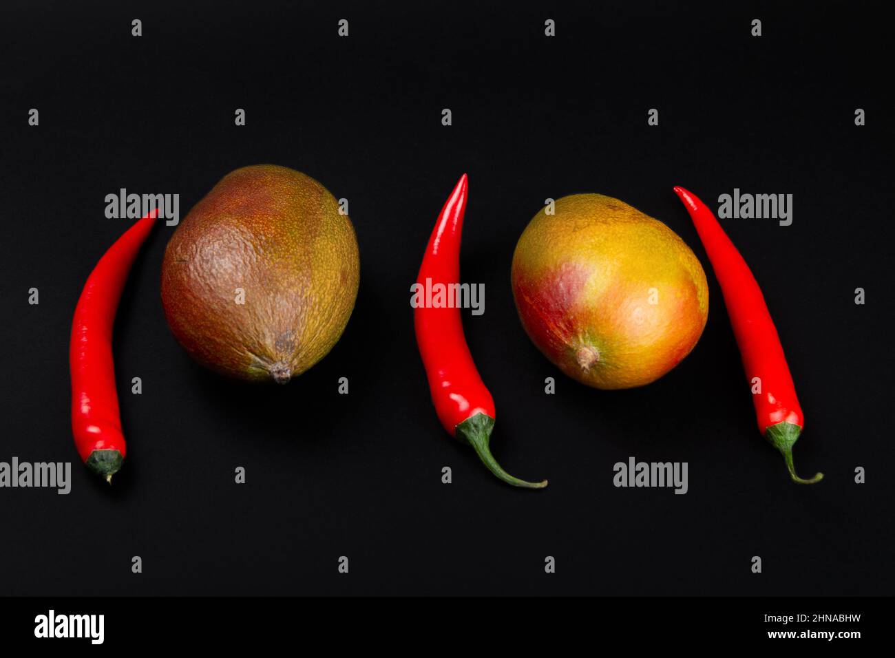 Whole mangoes and chili peppers on black background Stock Photo - Alamy