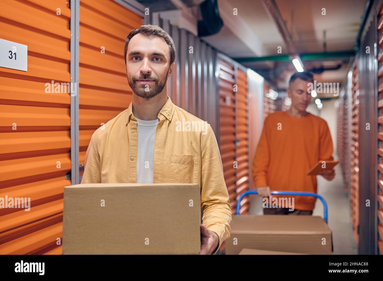 Two men unloading goods in the warehouse Stock Photo - Alamy