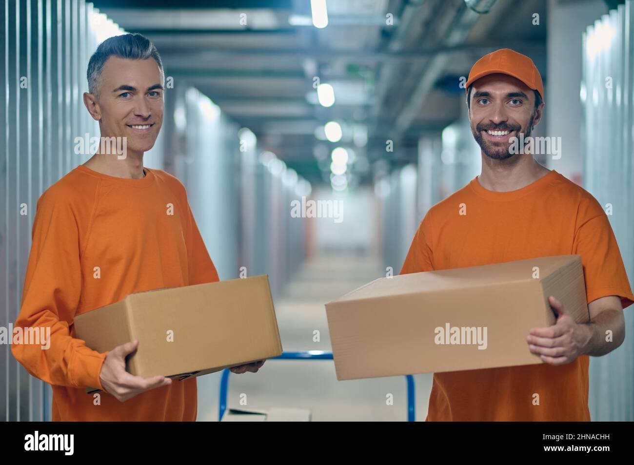 Two storehouse loaders holding cardboard boxes and looking ahead Stock ...
