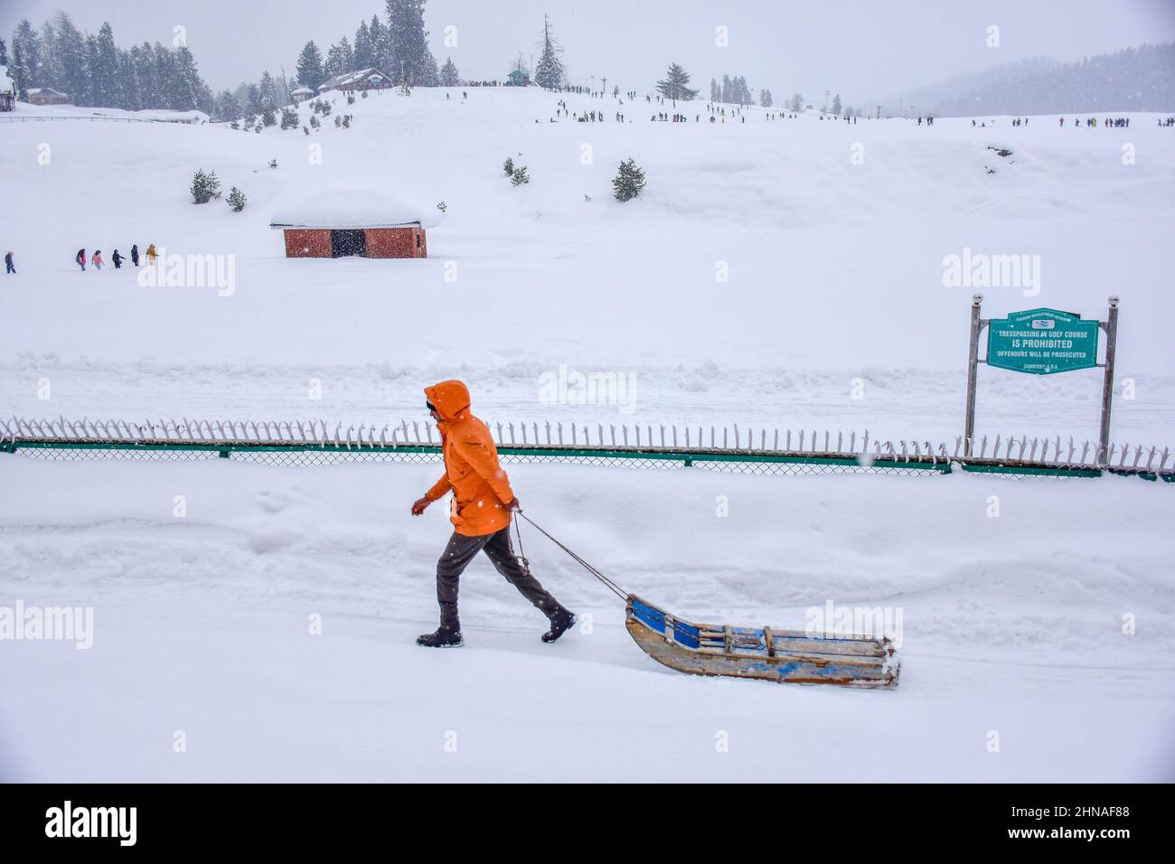 A man with a sledge walks through a snow covered road during a snowfall ...