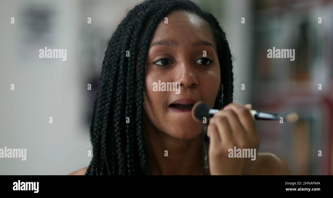 African black teen girl applying make-up in front of mirror Stock Photo ...