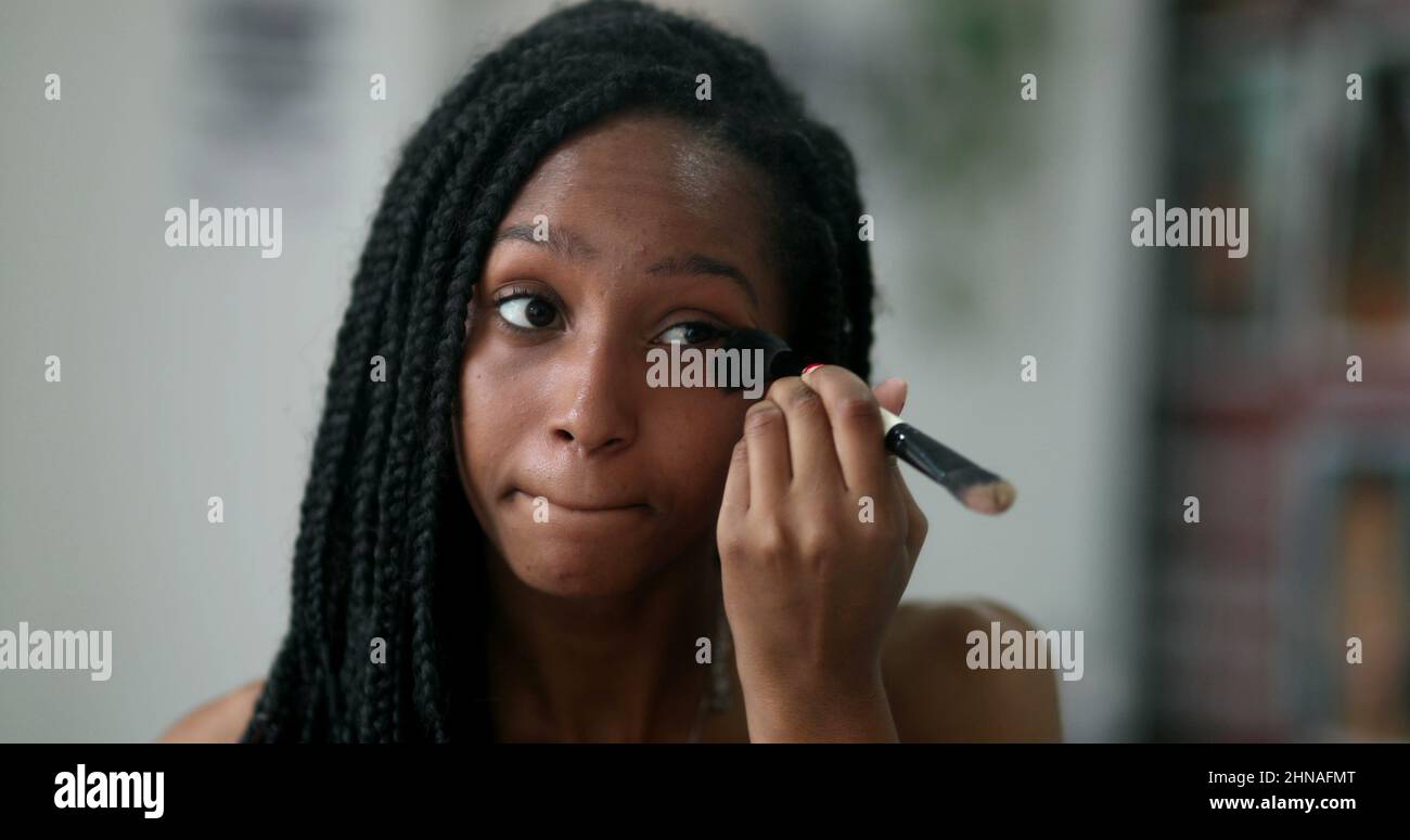 African black teen girl applying make-up in front of mirror Stock Photo ...