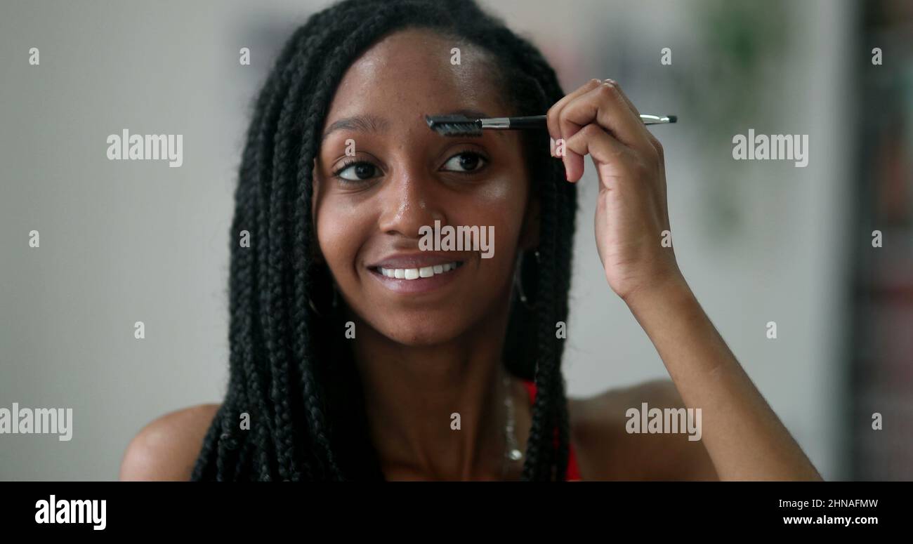 African black teen girl applying make-up in front of mirror Stock Photo ...