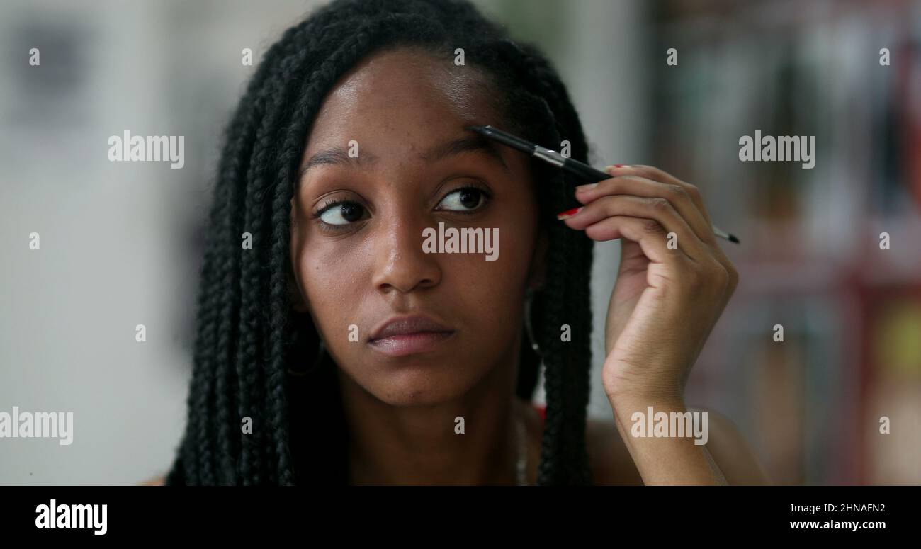 African black teen girl applying make-up in front of mirror Stock Photo ...