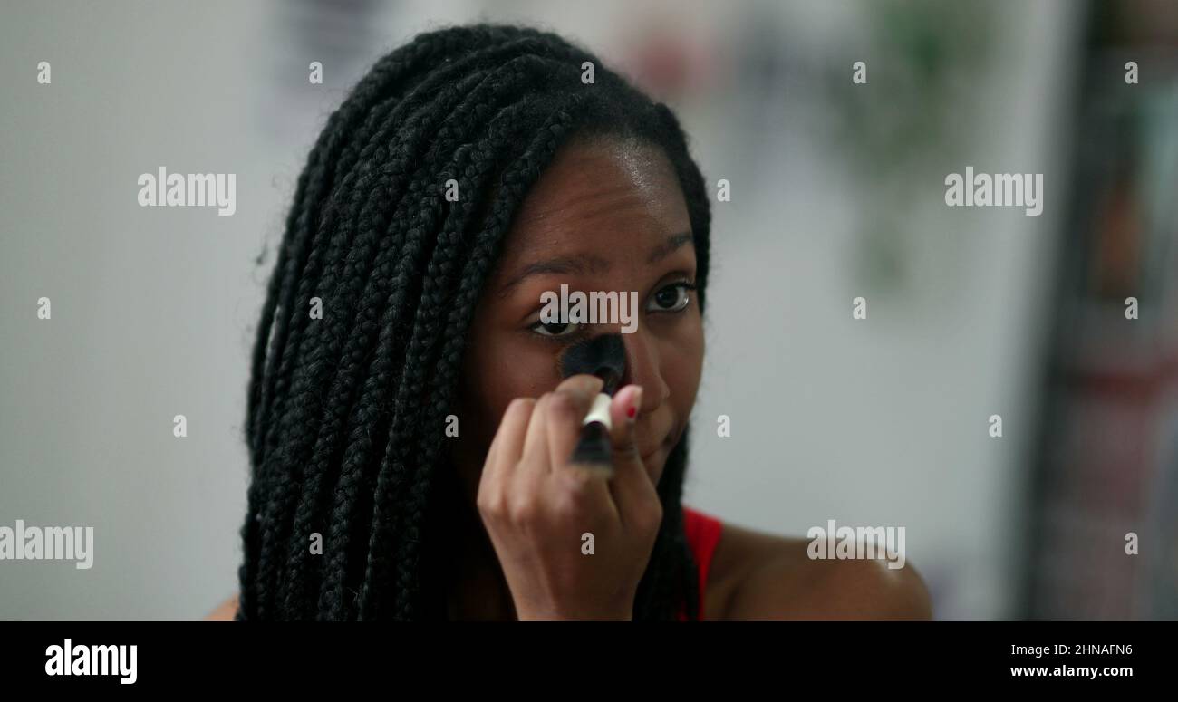 African black teen girl applying make-up in front of mirror Stock Photo ...