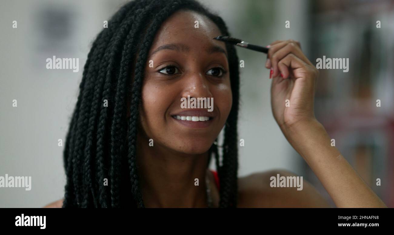 African black teen girl applying make-up in front of mirror Stock Photo ...