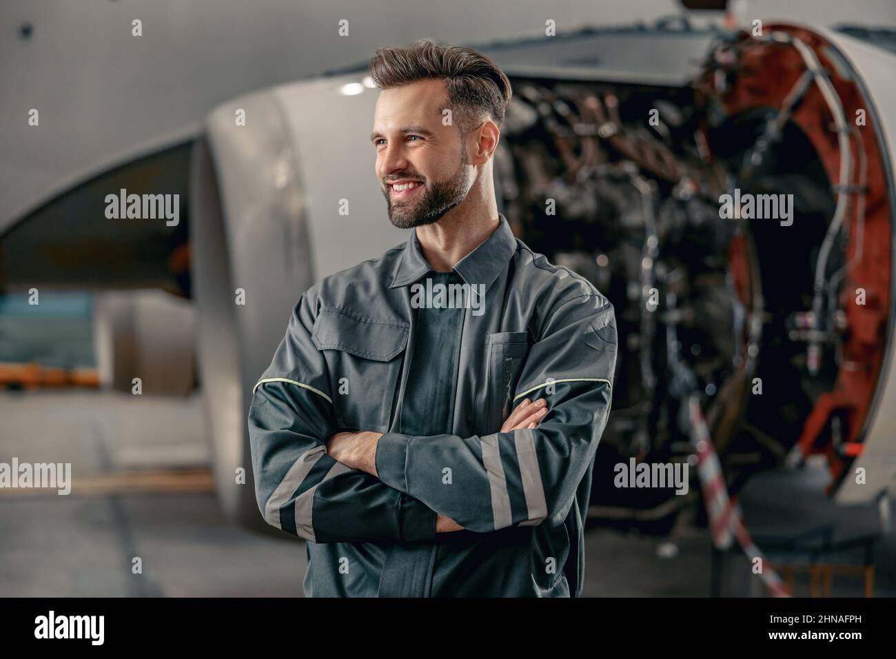 Cheerful airline mechanic standing near airplane in hangar Stock Photo ...