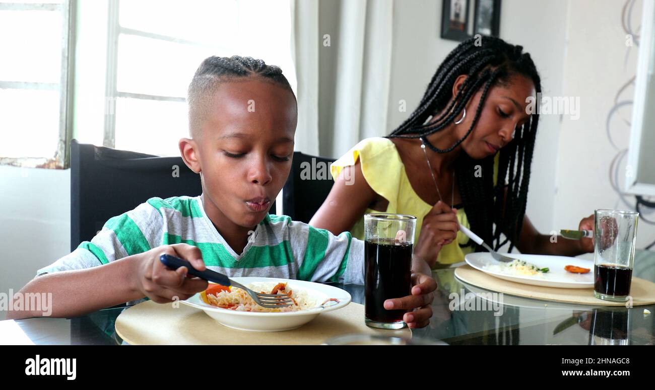 Black family eating lunch, little boy and teenage girl eating meal ...