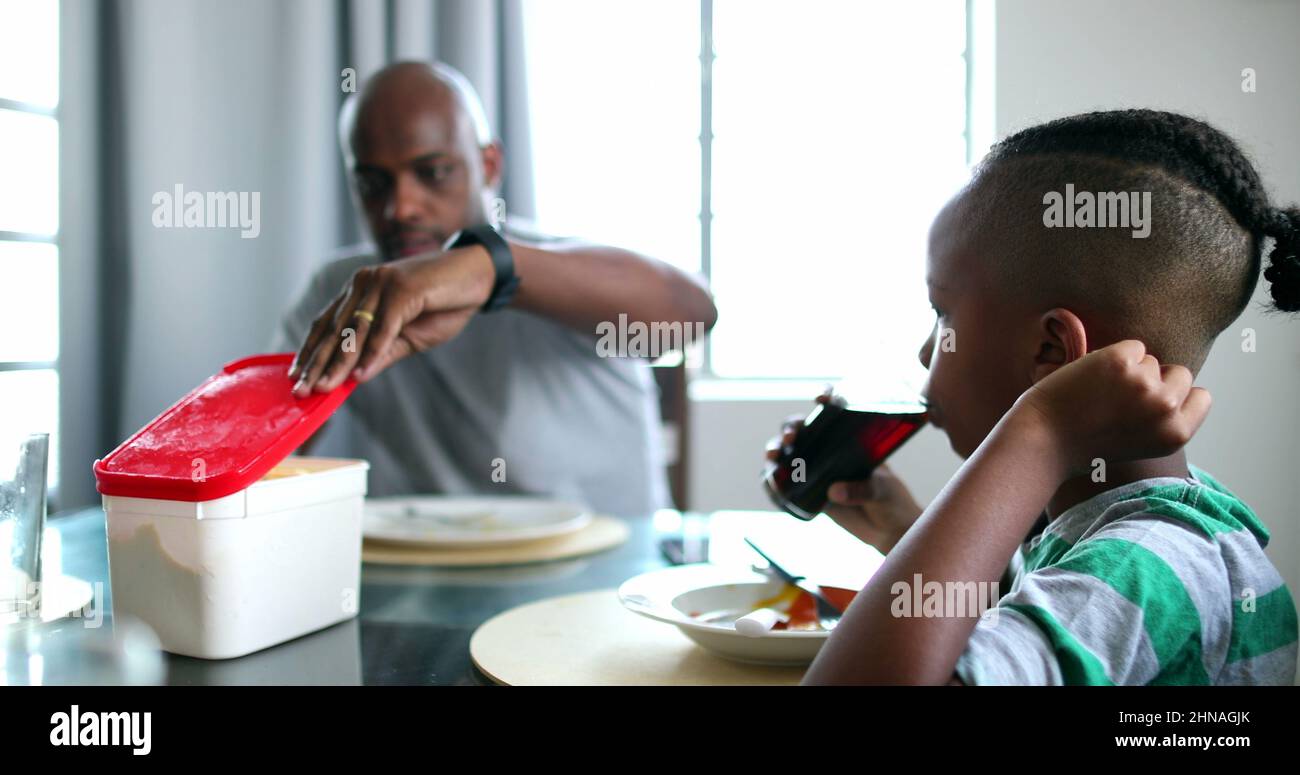 Candid black African family eating lunch, dad putting away phone, child ...