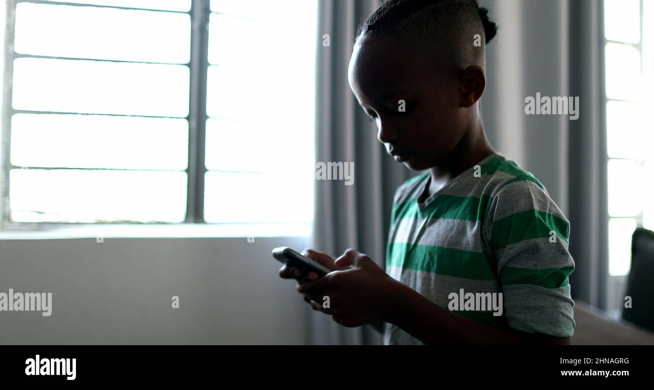Child holding smartphone device. Mixed race black african boy kid using ...