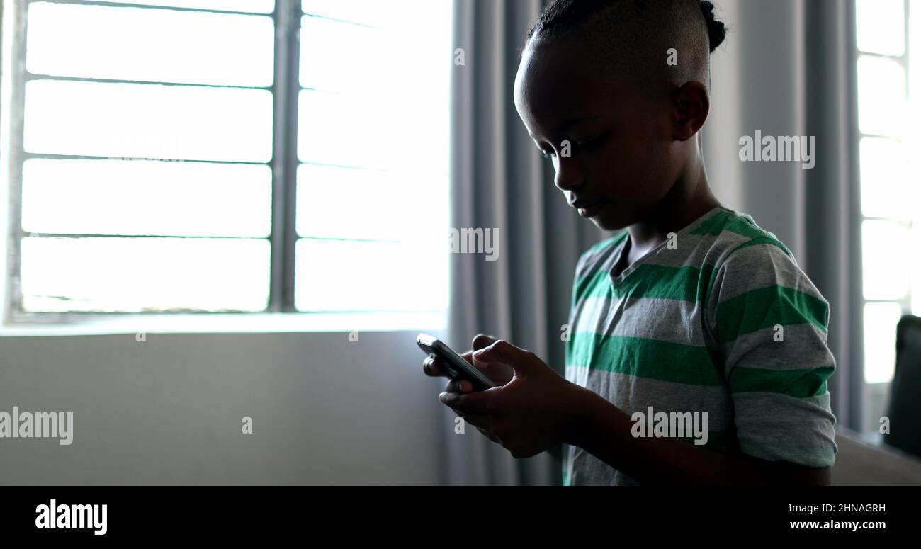 Child holding smartphone device. Mixed race black african boy kid using ...
