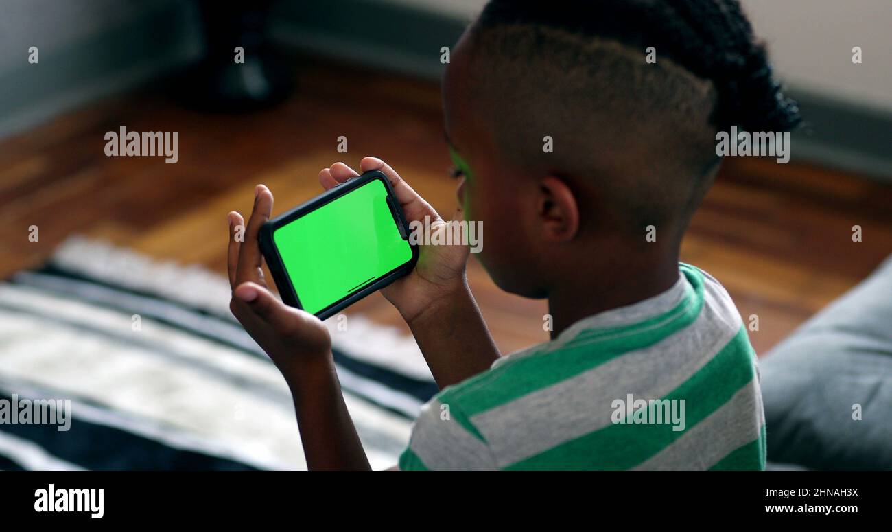 Small boy watching content on phone. Green screen mock-up. African ...