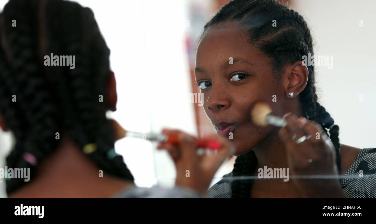 Teenage african girl applying make-up in front of mirror Stock Photo ...