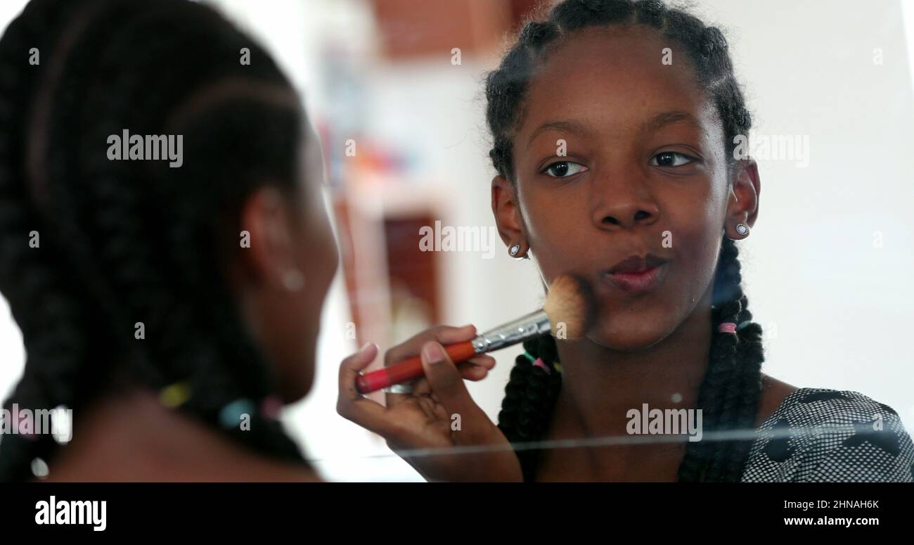 Teenage african girl applying make-up in front of mirror Stock Photo ...