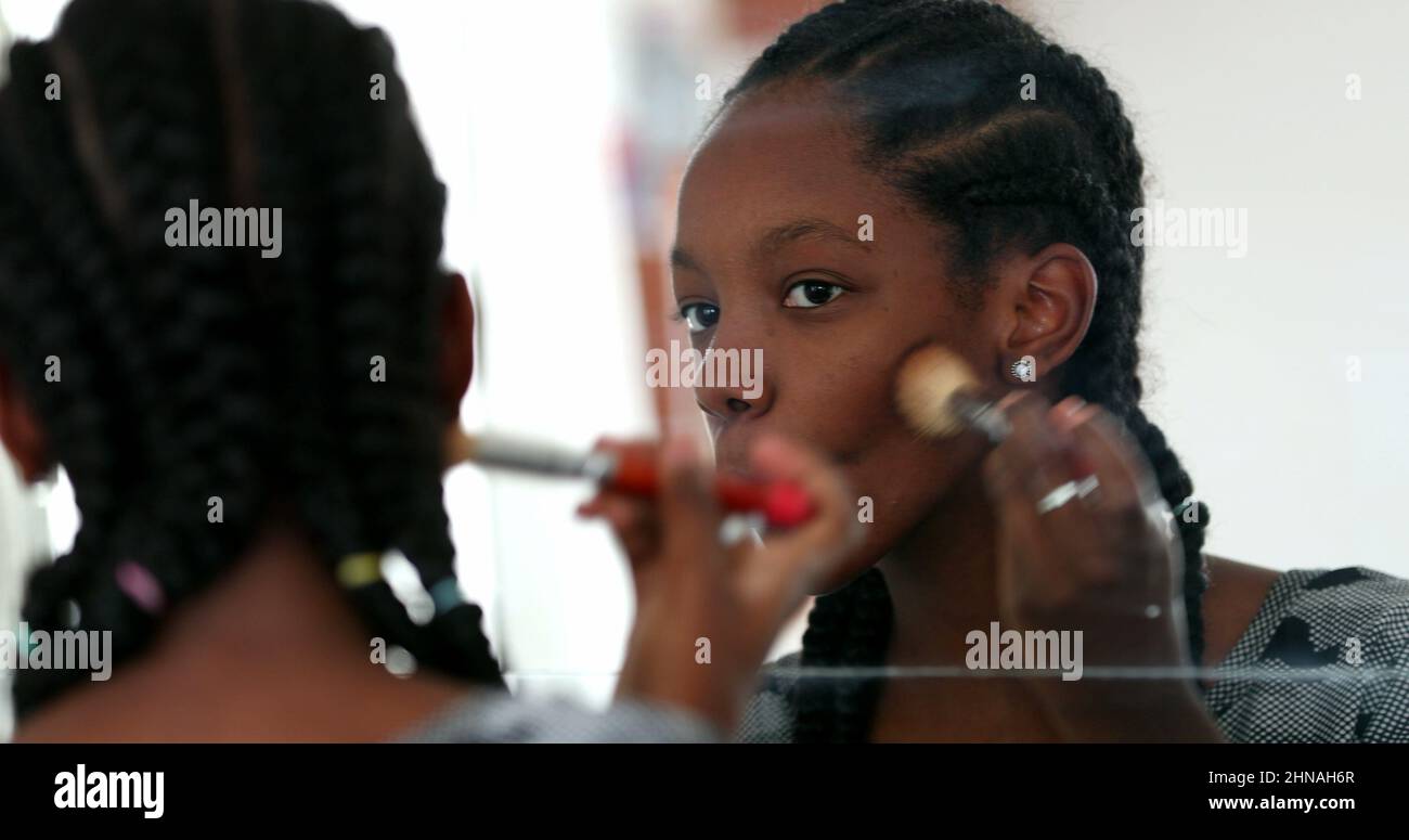 Teenage african girl applying make-up in front of mirror Stock Photo ...