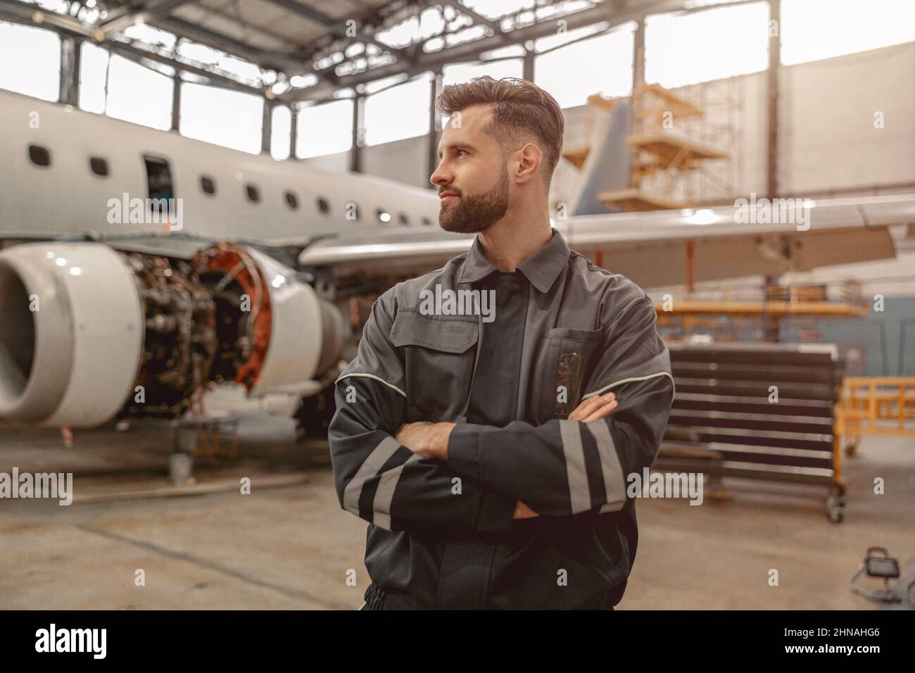 Bearded man aviation mechanic standing in hangar Stock Photo - Alamy