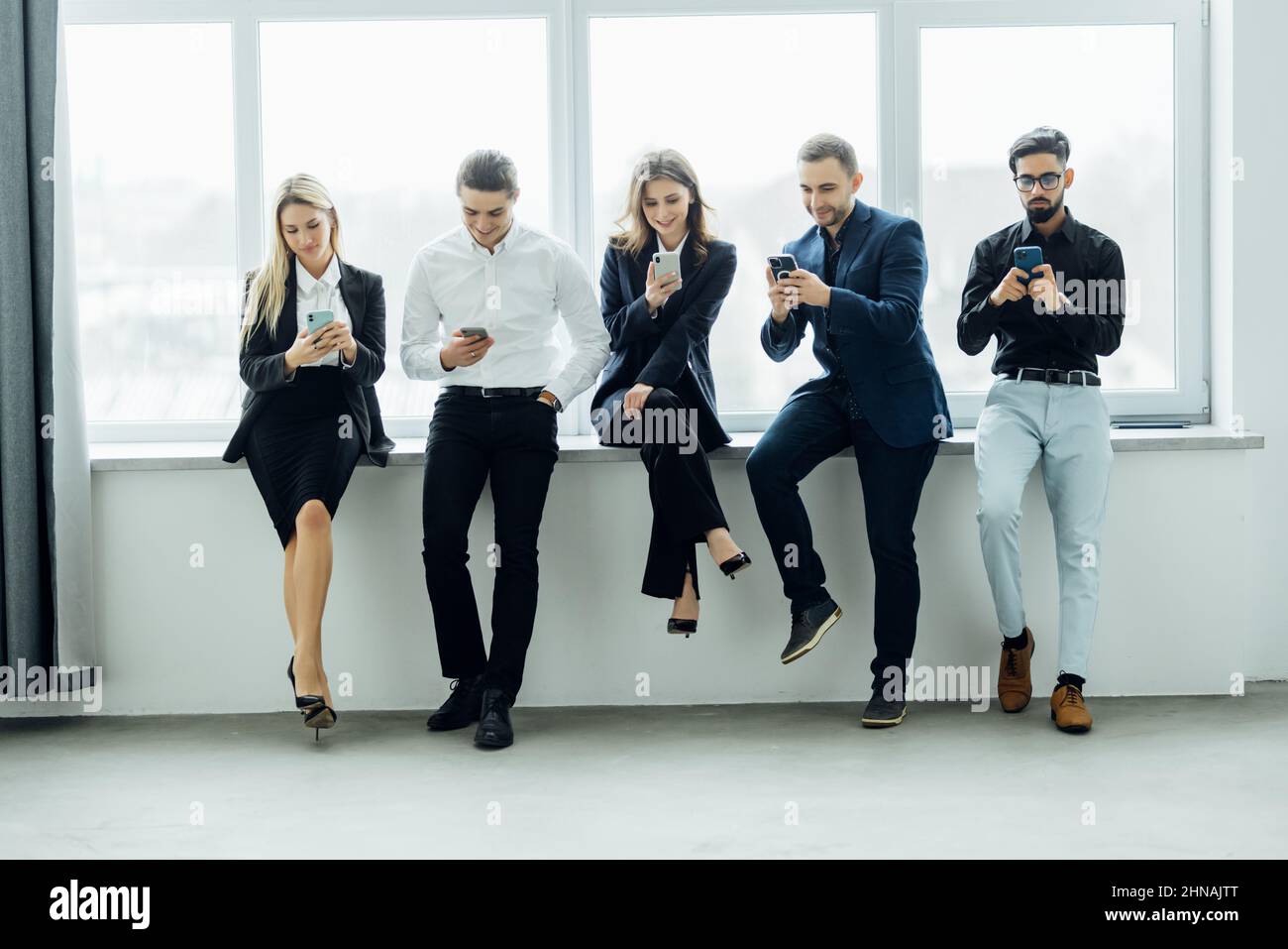 business colleagues with their smartphones sitting in the office hallway Stock Photo - Alamy