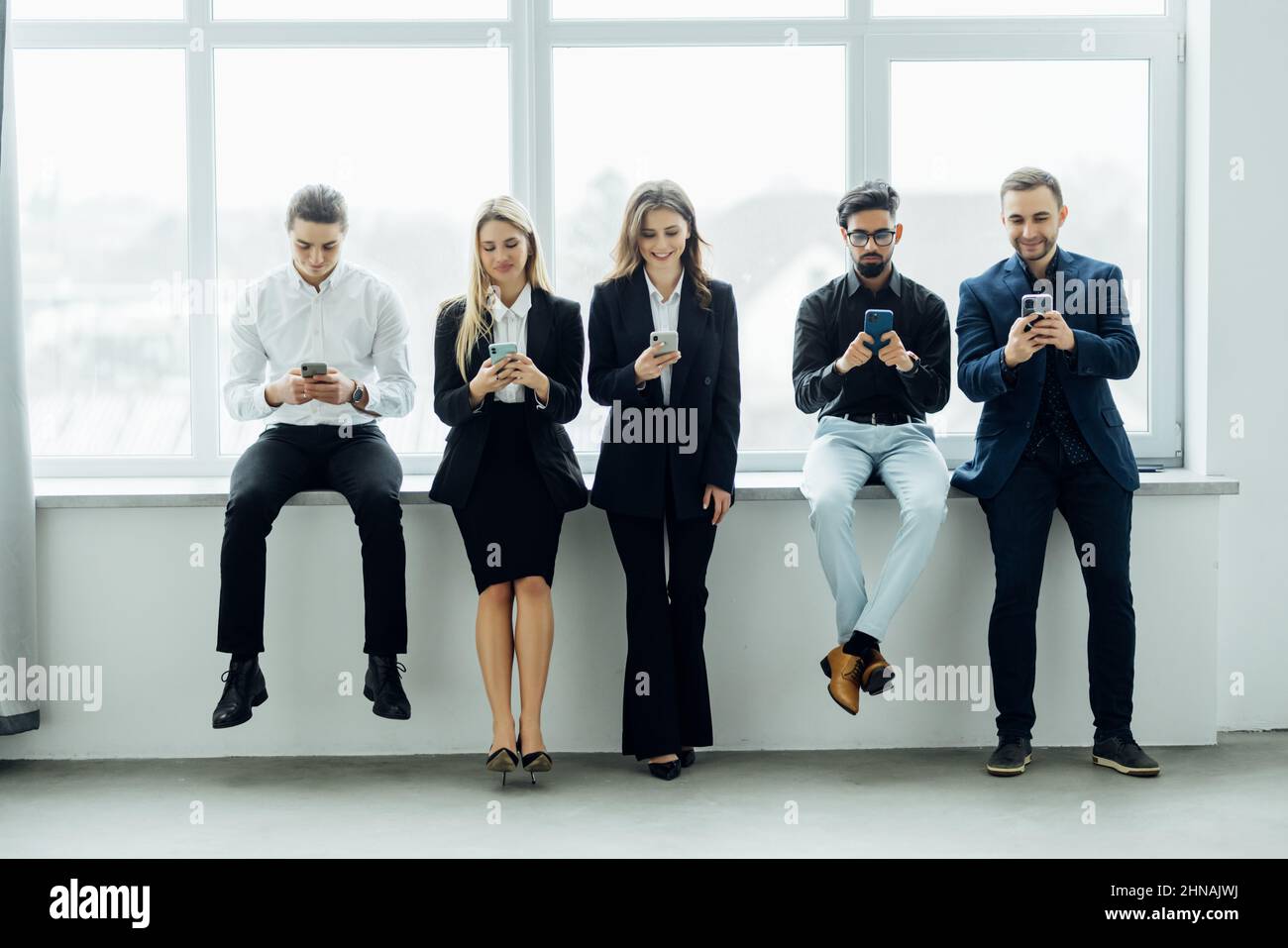 Group of business people using mobile phones and sitting on couch ...