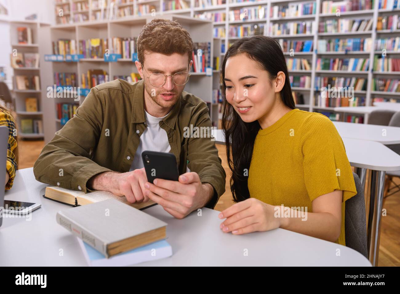 University students are studying in a library together as teamwork for ...