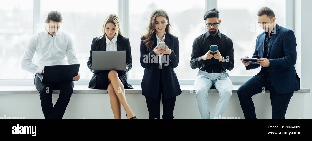business colleagues with their smartphones sitting in the office ...