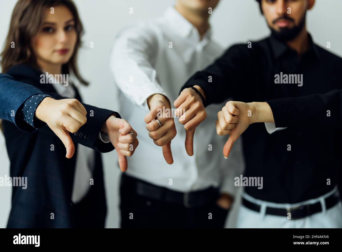 Mixed team showing thumb down Stock Photo - Alamy