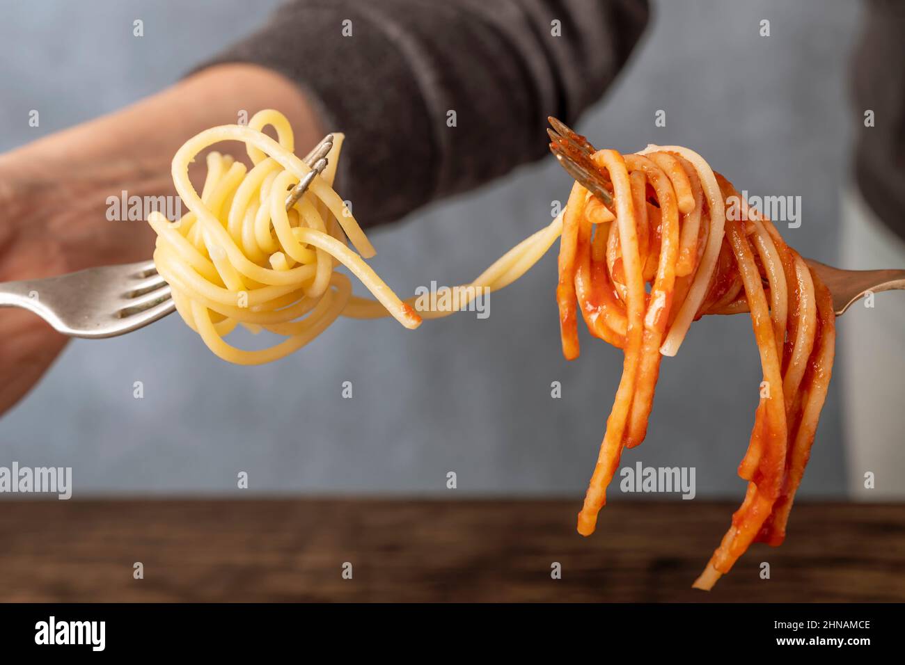 Two forks with white spaghetti on one side and spaghetti with tomato ...