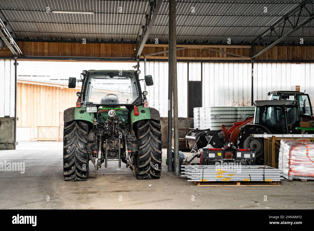 Green tractor with big wheels in garage near agricultural fixtures at ...