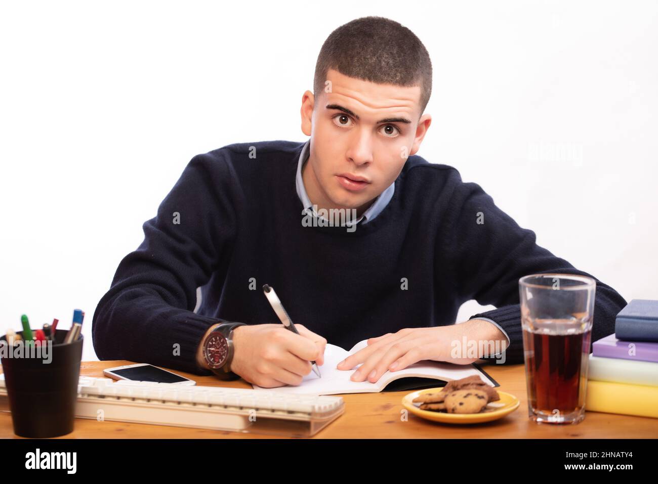 young men writing in a book and working in the computer at home, online ...
