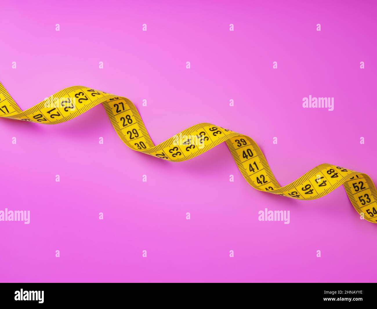 Yellow spiral tape measure on violet background with copyspace Stock ...
